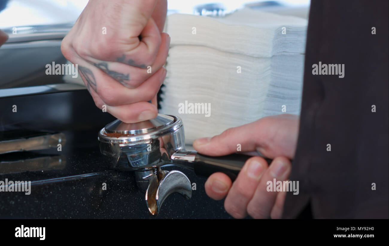 Barista presses ground coffee using tamper Stock Photo - Alamy