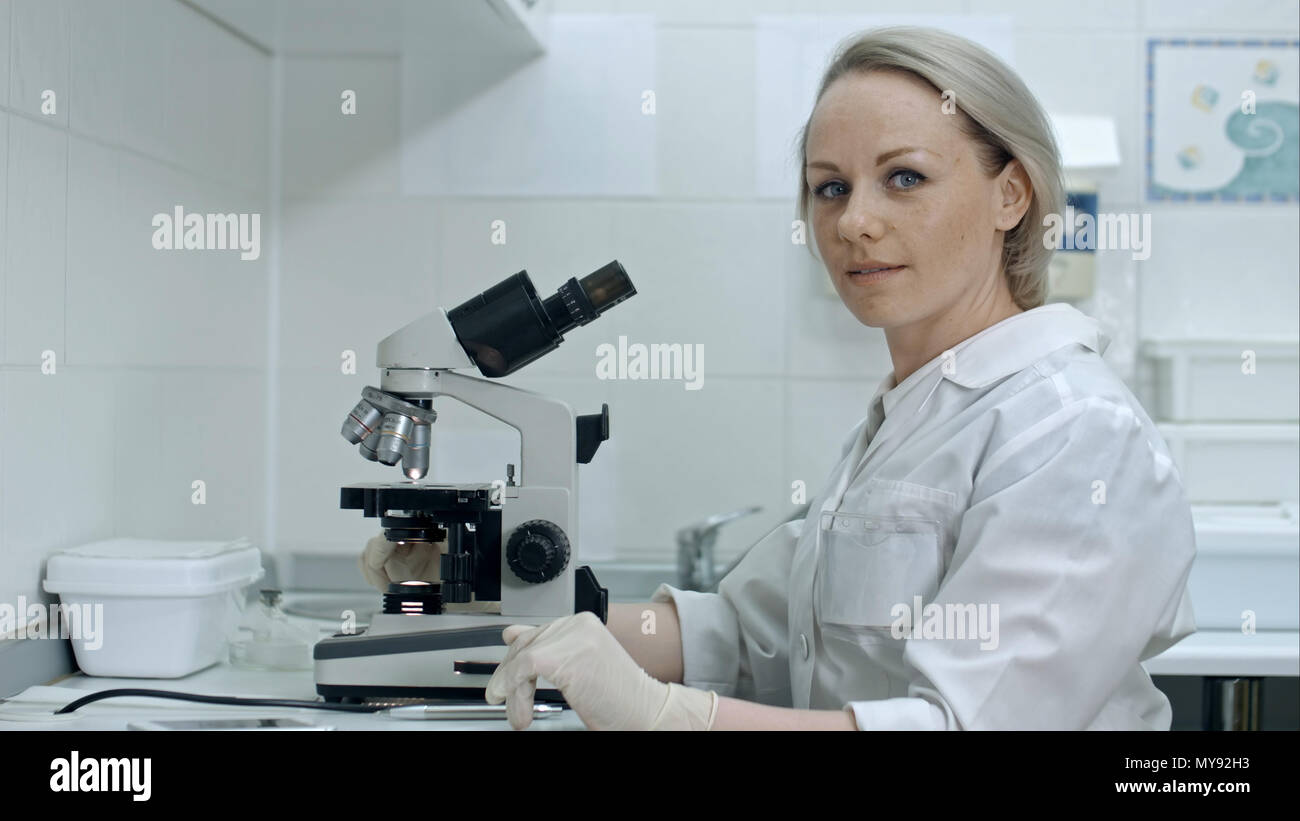 Pretty female with microscope looking at camera in laboratory Stock ...