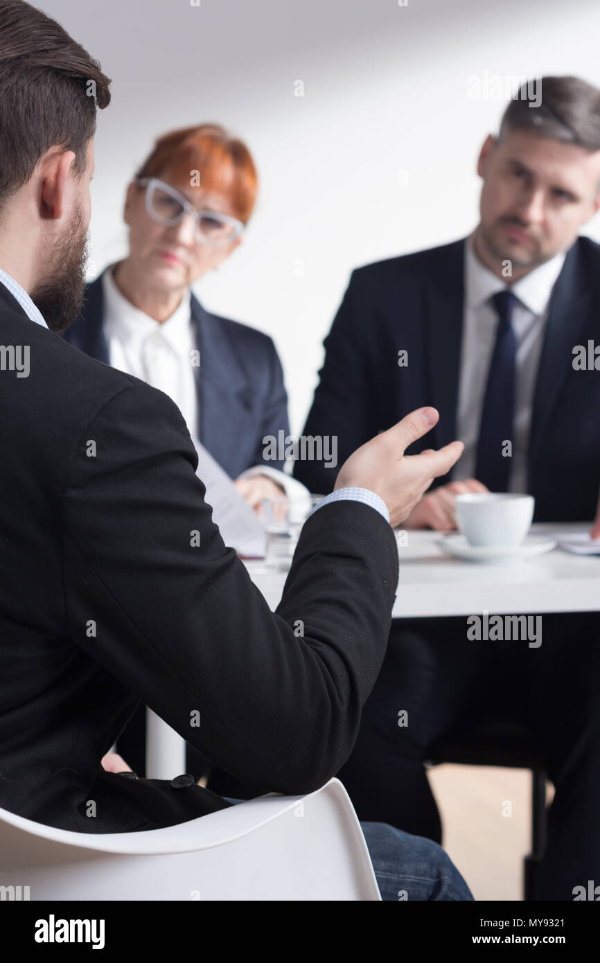 Man back view during interview and two businesspeople Stock Photo - Alamy