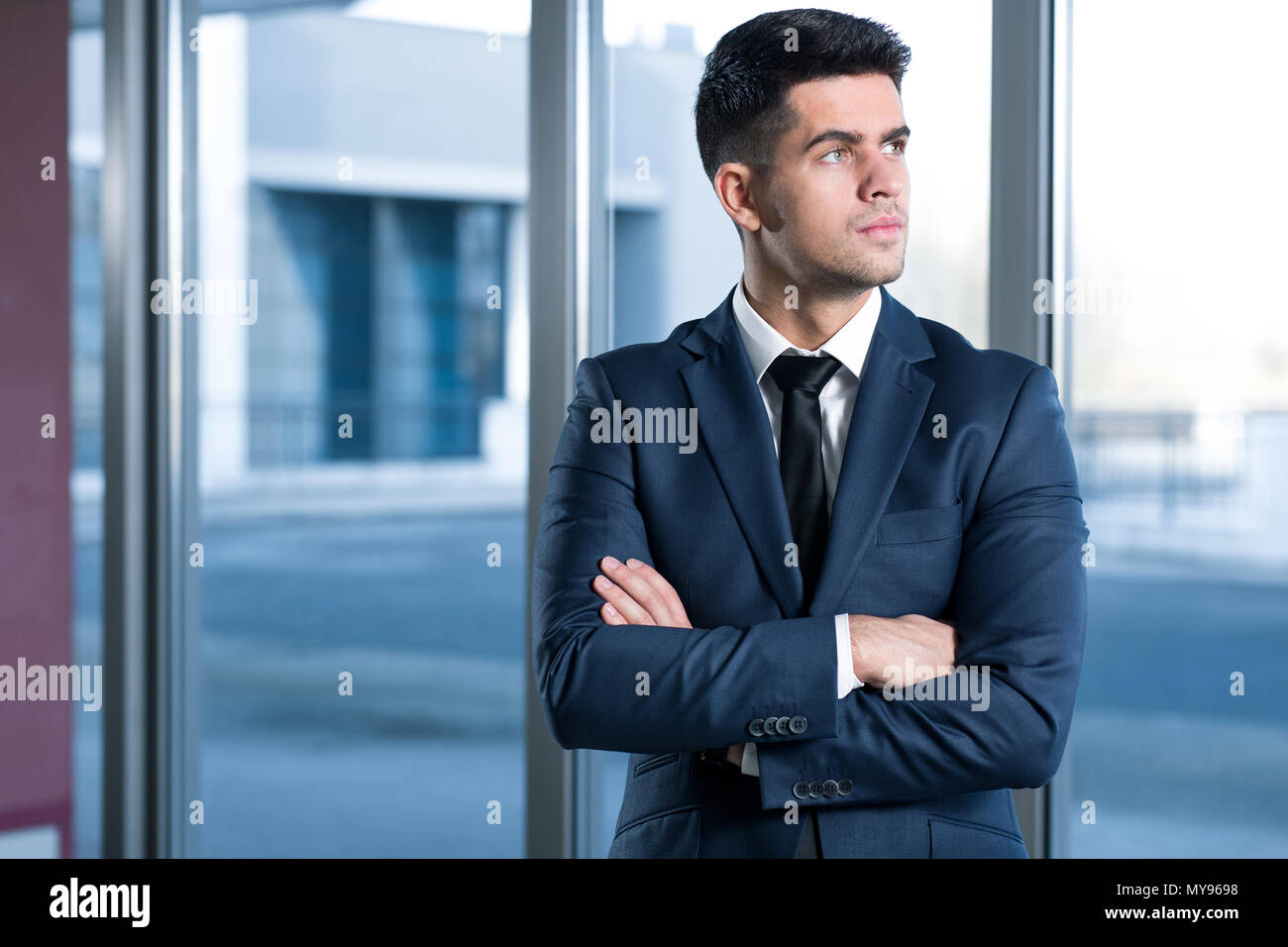 Handsome businessman in suit standing in office building Stock Photo ...