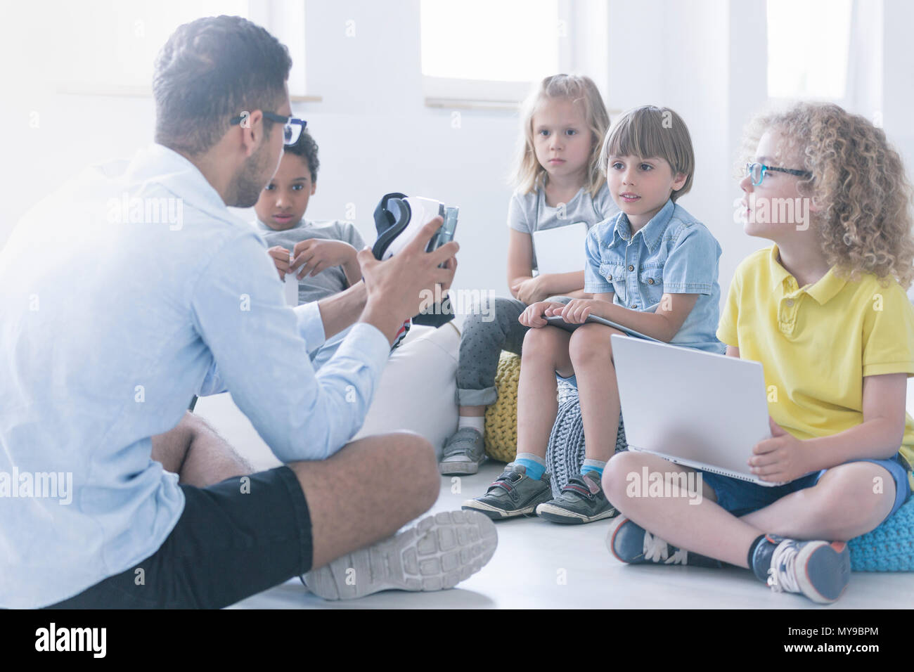Happy teacher shows children how the robot works during robotics lesson ...