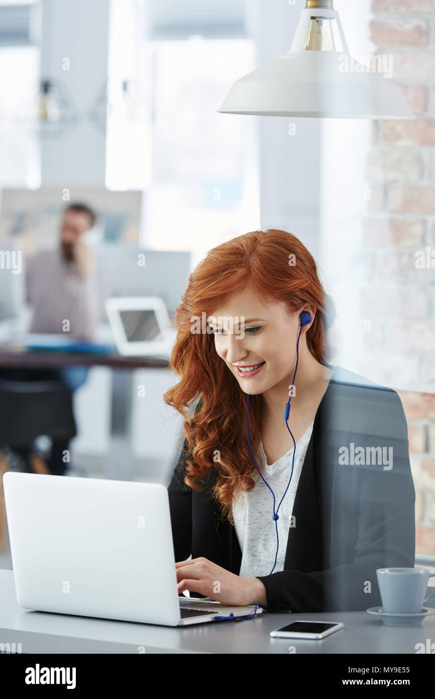 Office worker using laptop and listening to music while working Stock ...