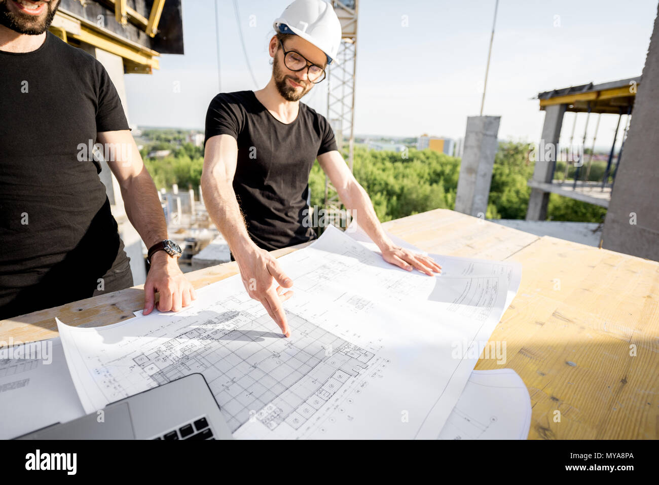 Workers with drawings at the construction site Stock Photo - Alamy