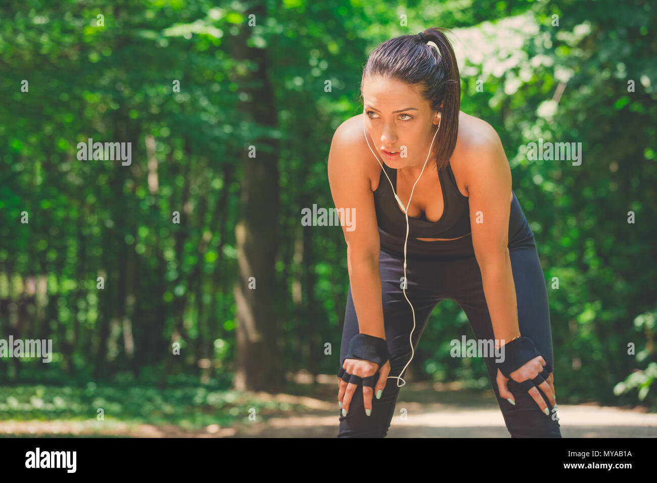 Beautiful female runner taking a brake after morning exercise in nature ...