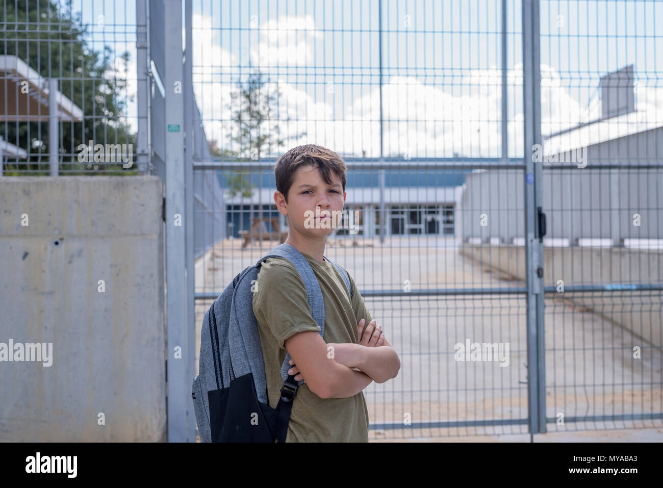 Cheerful child carrying his backpack standing in front of the school ...