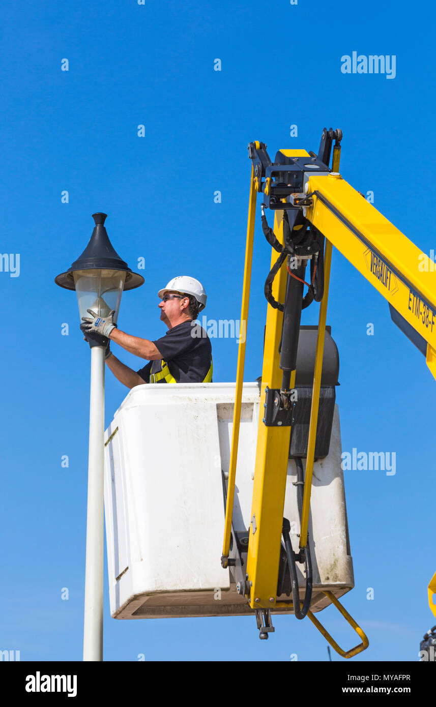 man checking and changing lightbulb light bulb in street lamp along ...