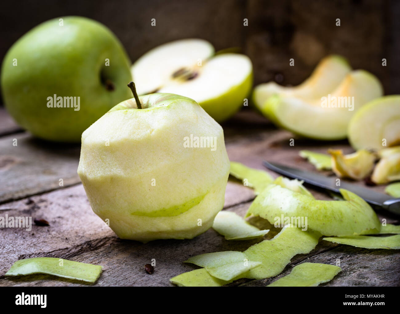 Green apple on wooden desk with knife and halved apples behind Stock ...