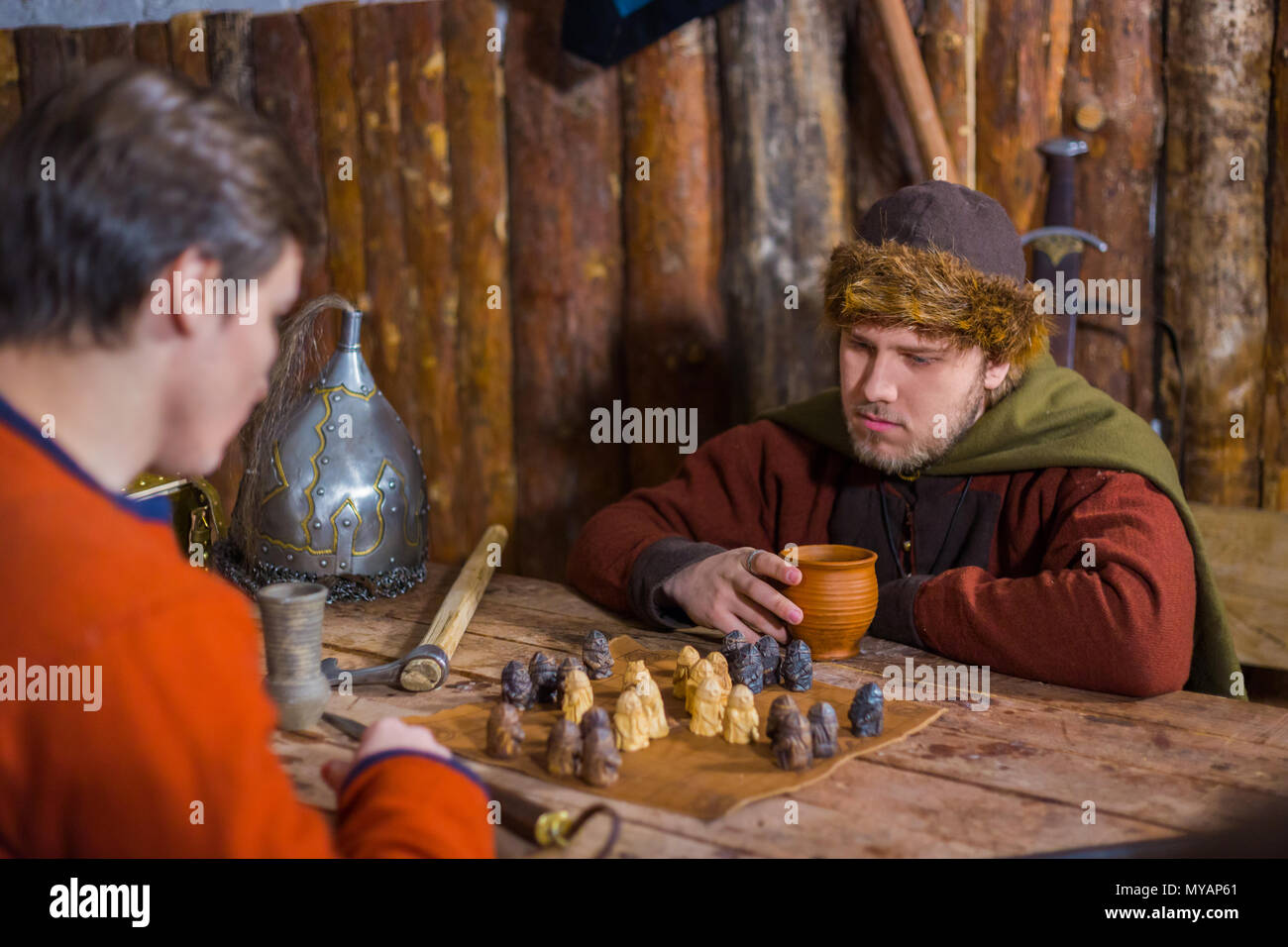 Portrait of man in russian ethnic suit playing board game like chess ...