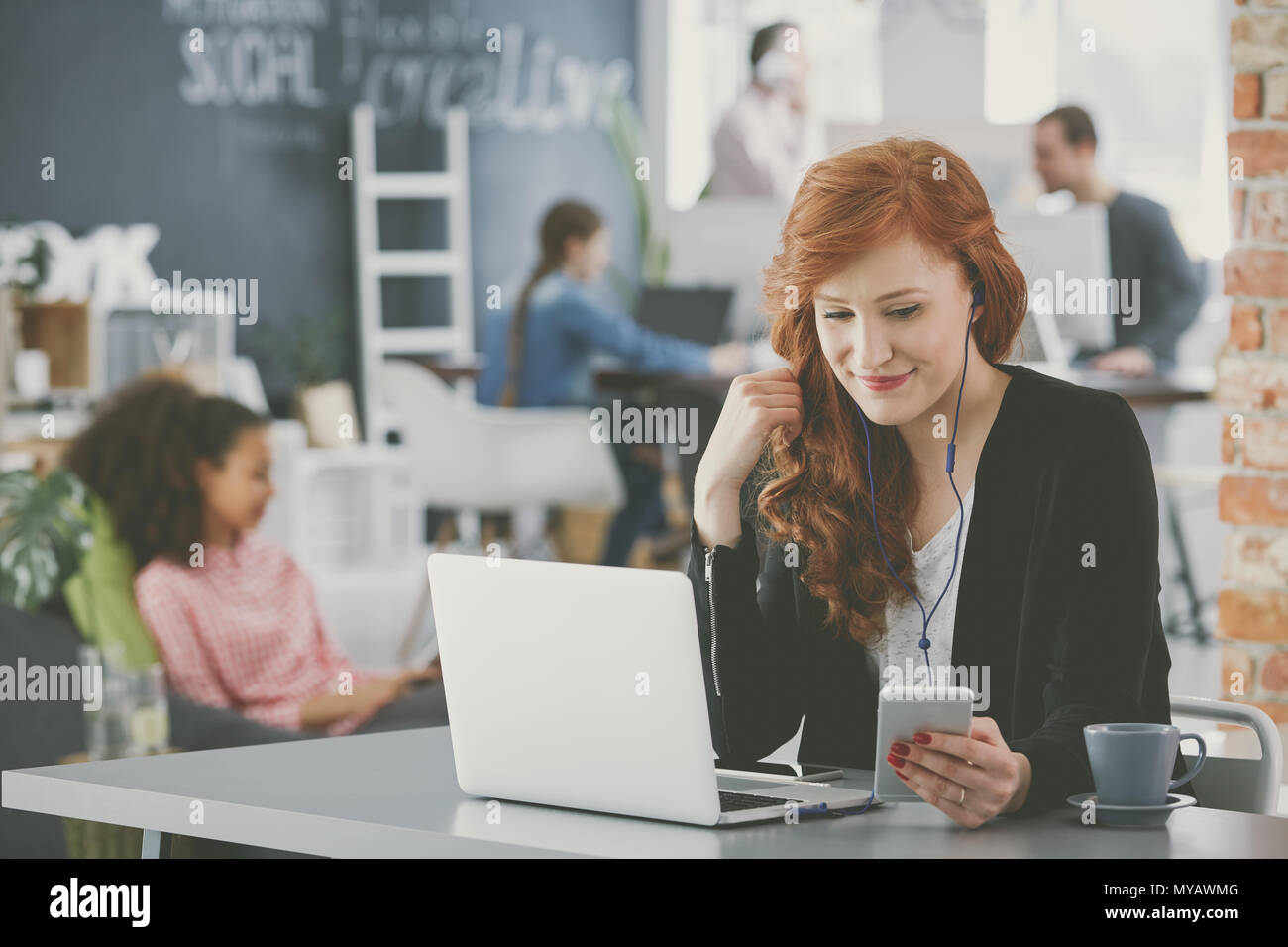 Woman using computer, listening to music while working Stock Photo - Alamy