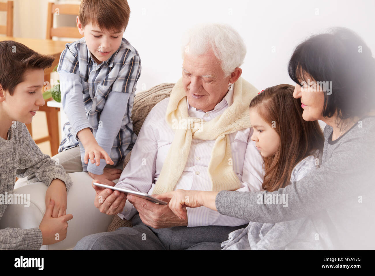 Grandchildren teaching grandpa how to use tablet Stock Photo - Alamy