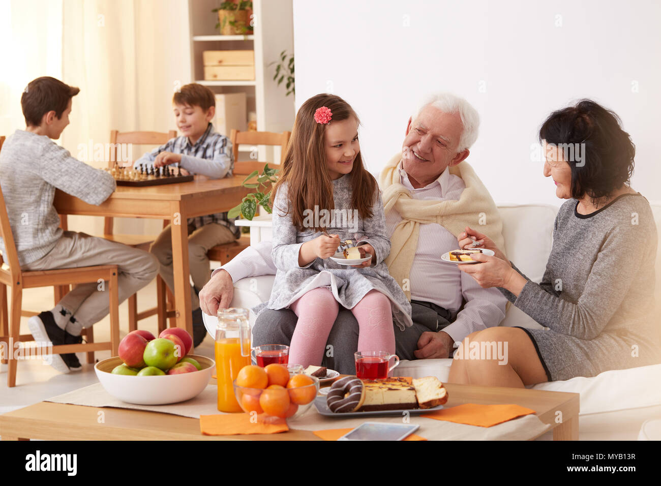 Happy family eating a cake in a living room Stock Photo - Alamy