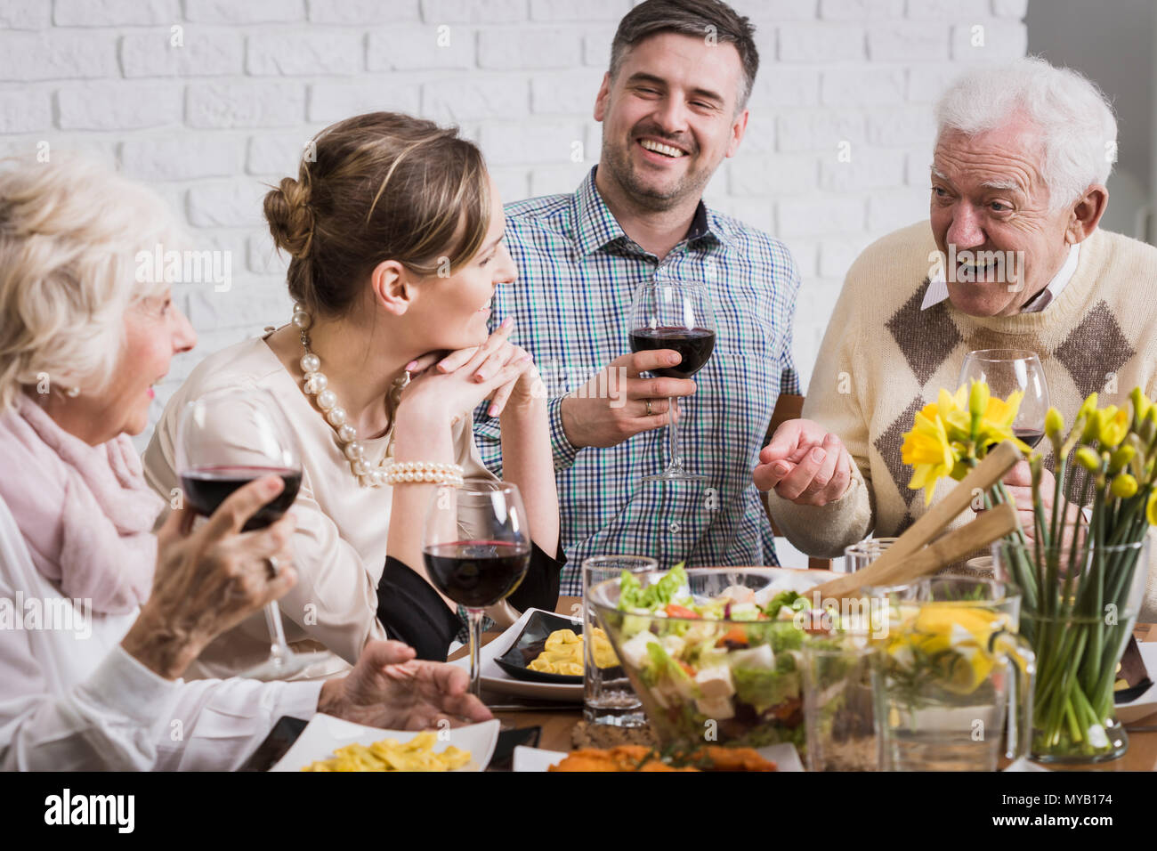 Happy family sitting beside table during dinner, smiling Stock Photo ...