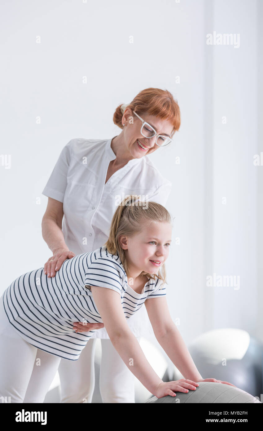 Child with spine deformity exercising with therapist in rehabilitation ...