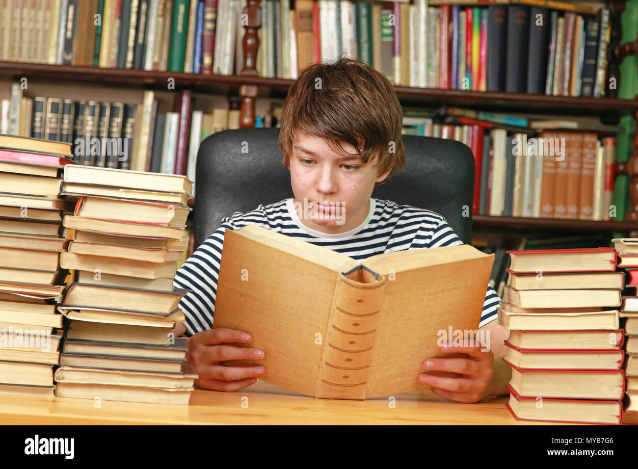 Teenage Boy Reading in School Library Stock Photo - Alamy