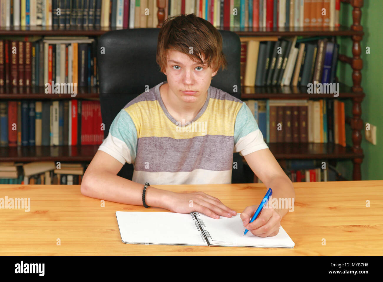 Teenage Boy Writing at Desk in Library Stock Photo - Alamy