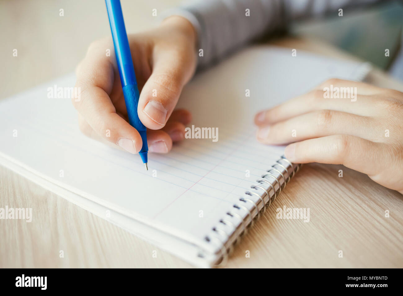 Kid holding pen and writing in notebook. Close up Stock Photo - Alamy