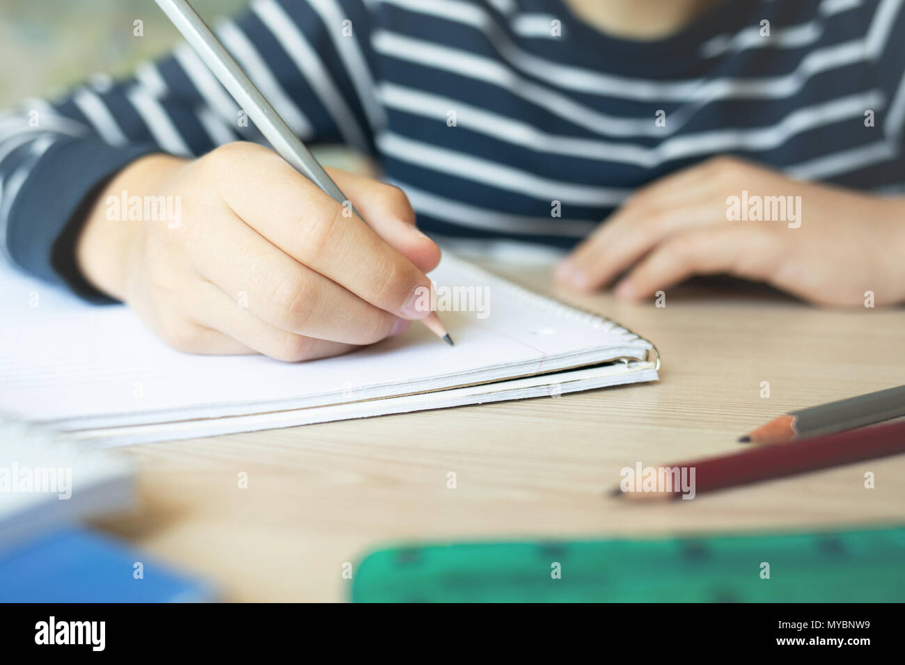 Kid holding pencil and writing in notebook. Close up Stock Photo - Alamy