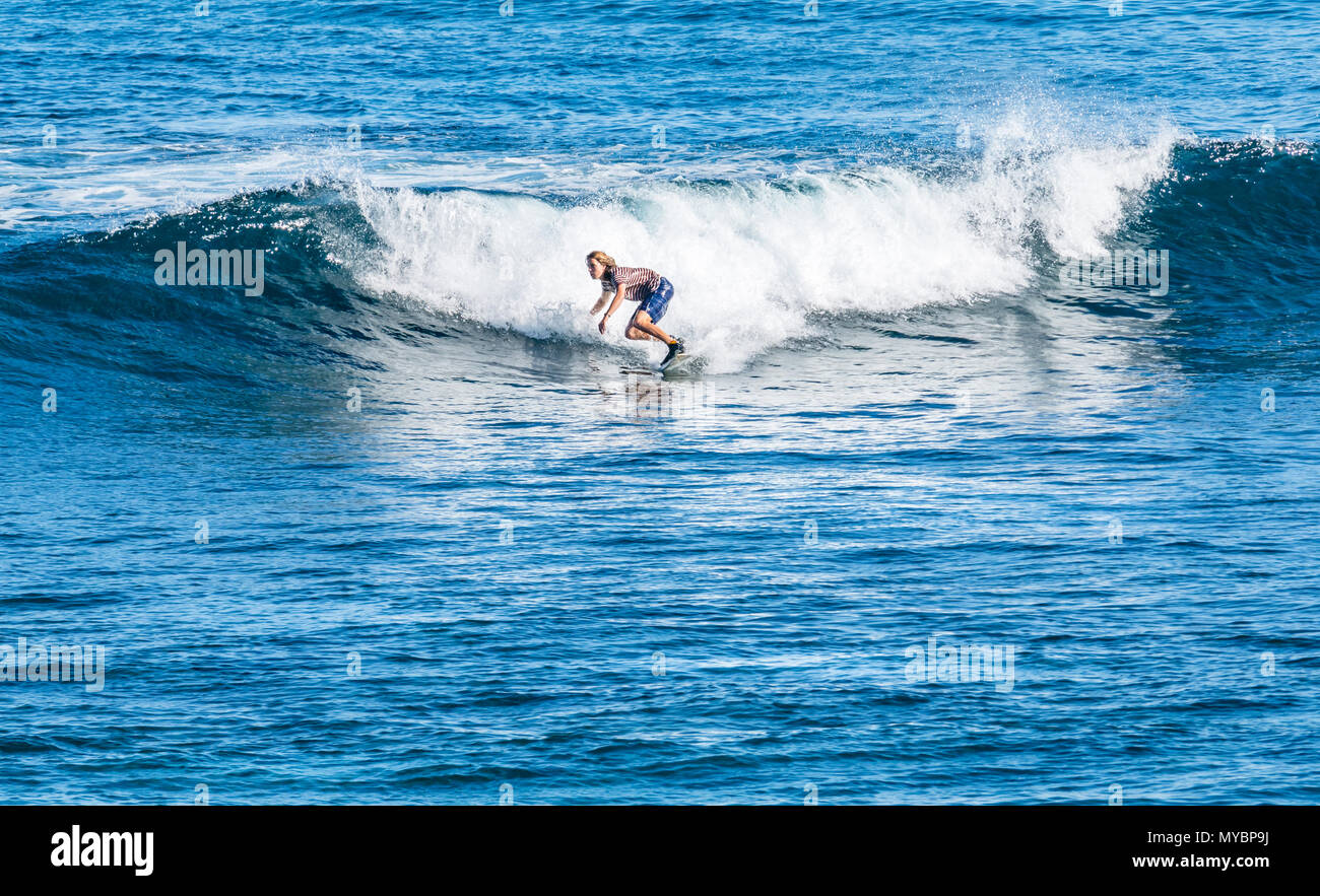 Young Caucasian man with long blonde hair surfing on wave in Pacific ...