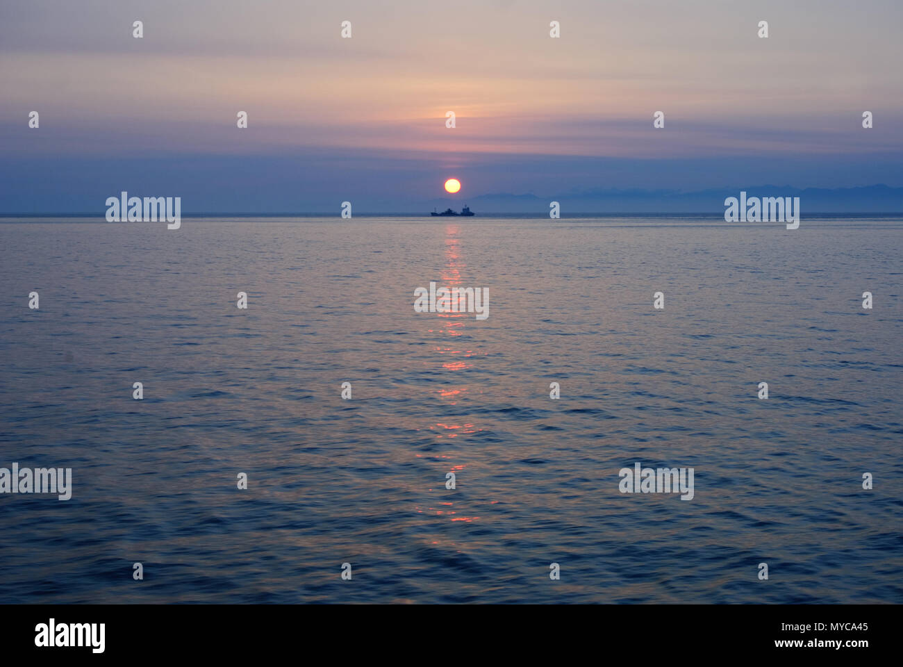 ship sailing in the ocean against sunset Stock Photo - Alamy