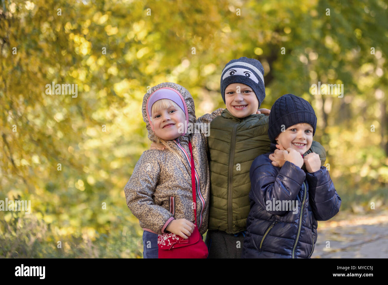 Group of happy three kids having fun outdoors in autumn park. Cute ...