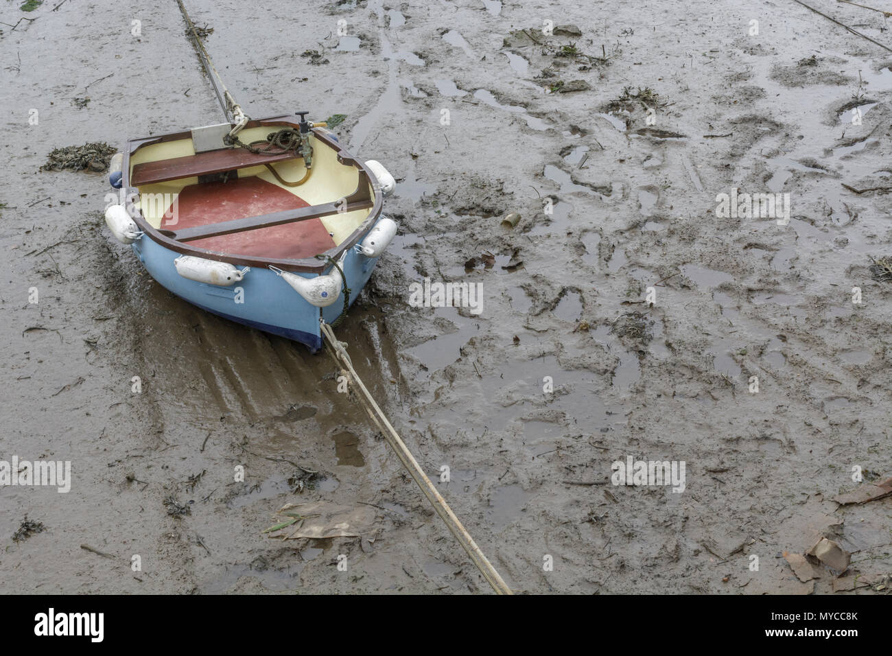 Small rowing boat beached on muddy river bank Stock Photo - Alamy
