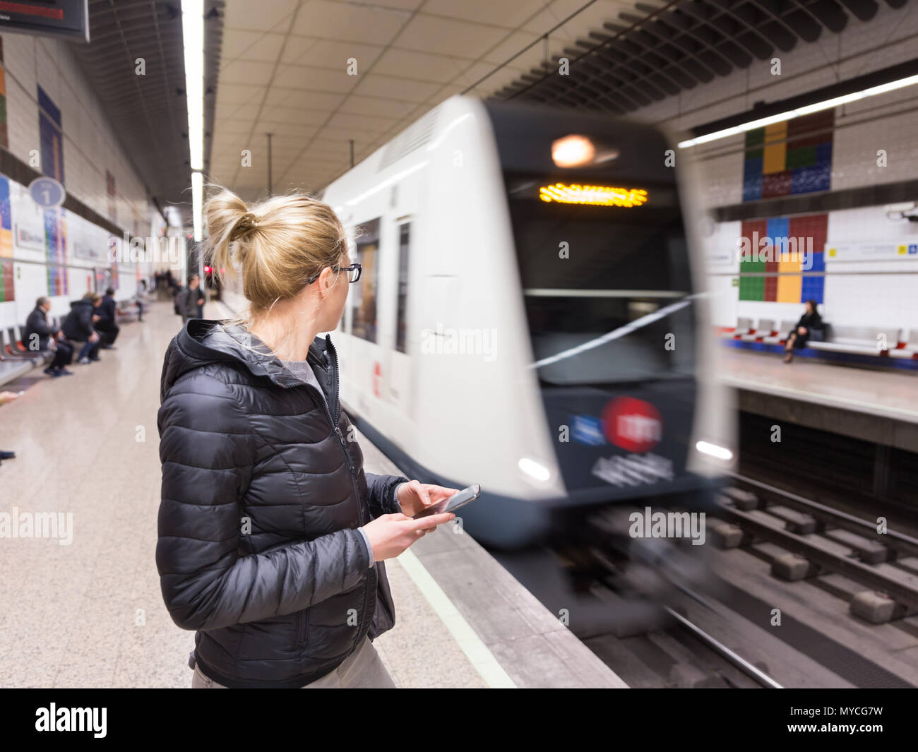 Woman with a cell phone waiting for metro Stock Photo - Alamy