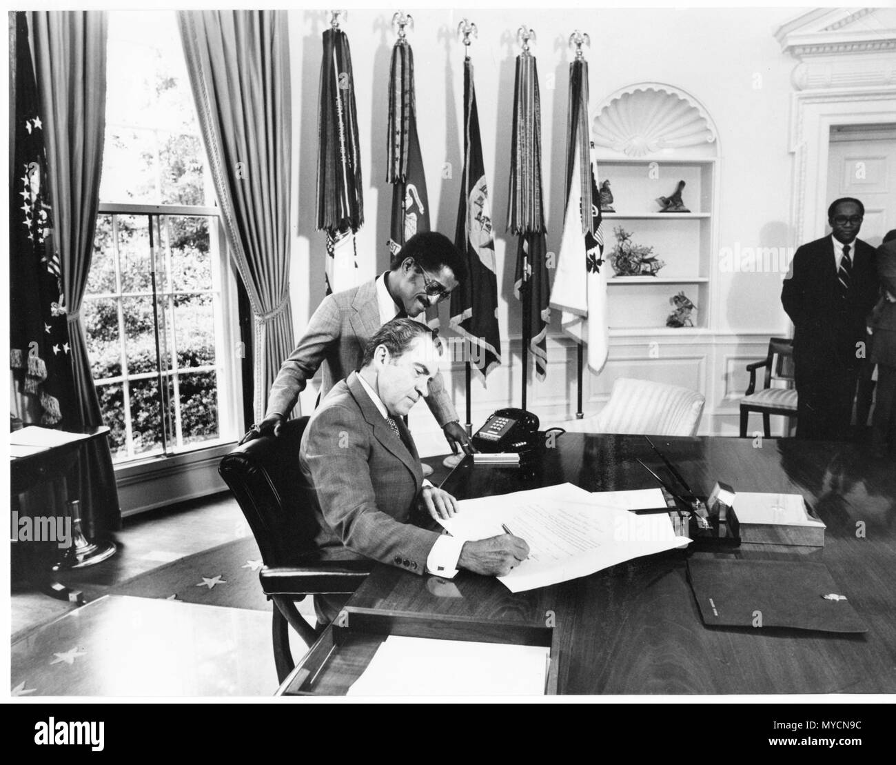 President Richard Nixon signing a paper while Sammy Davis, Jr Watches ...