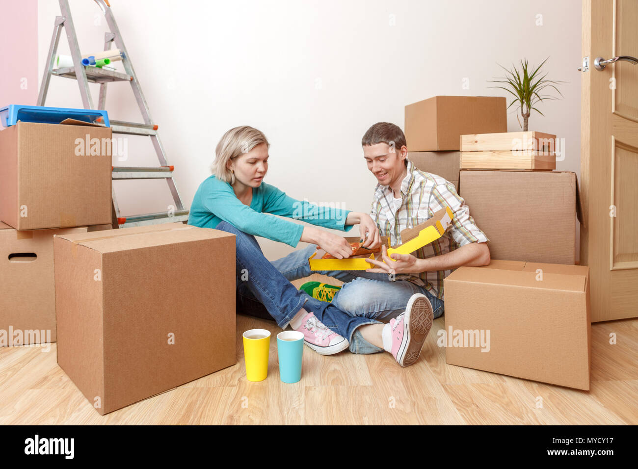 Photos of women and men eating pizza among cardboard boxes Stock Photo ...