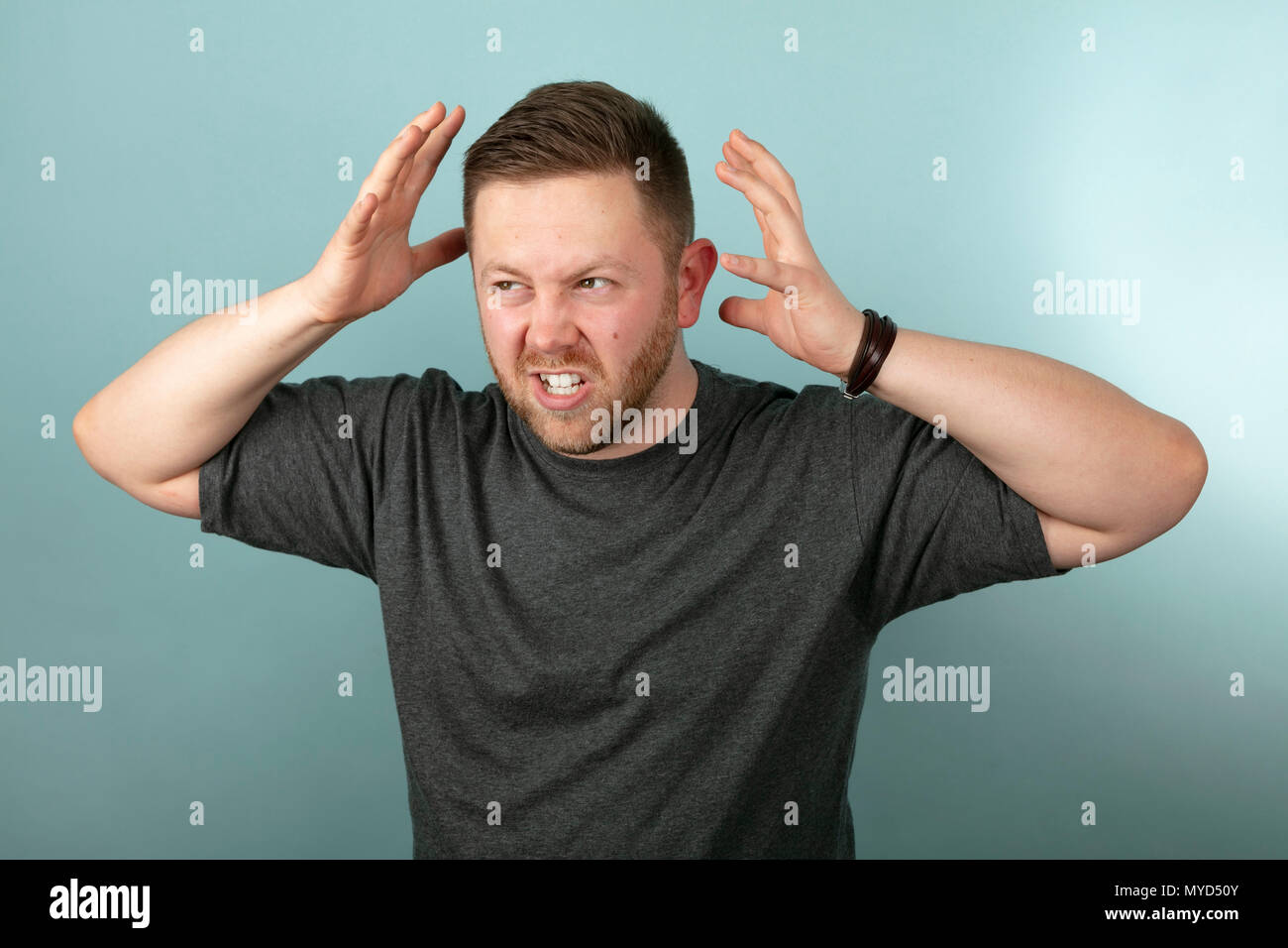 Frustrated angry man snarling and gesturing with his hands either side ...