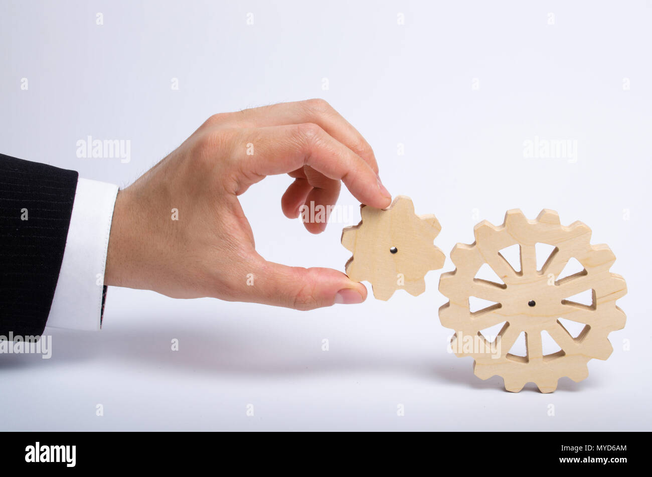hand of businessman in suit holds the gear to another gear wheel. The ...