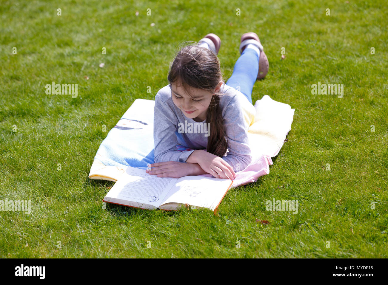 Girl lying on grass reading Stock Photo - Alamy