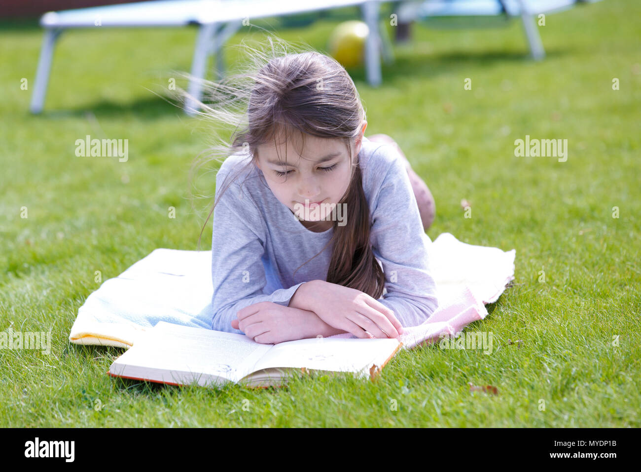 Girl lying on grass reading Stock Photo - Alamy