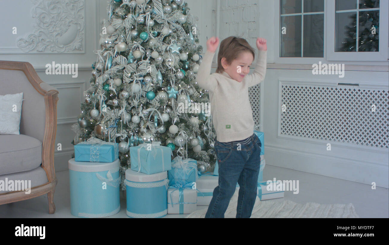 Happy little boy dancing next to the Christmas tree and presents Stock ...