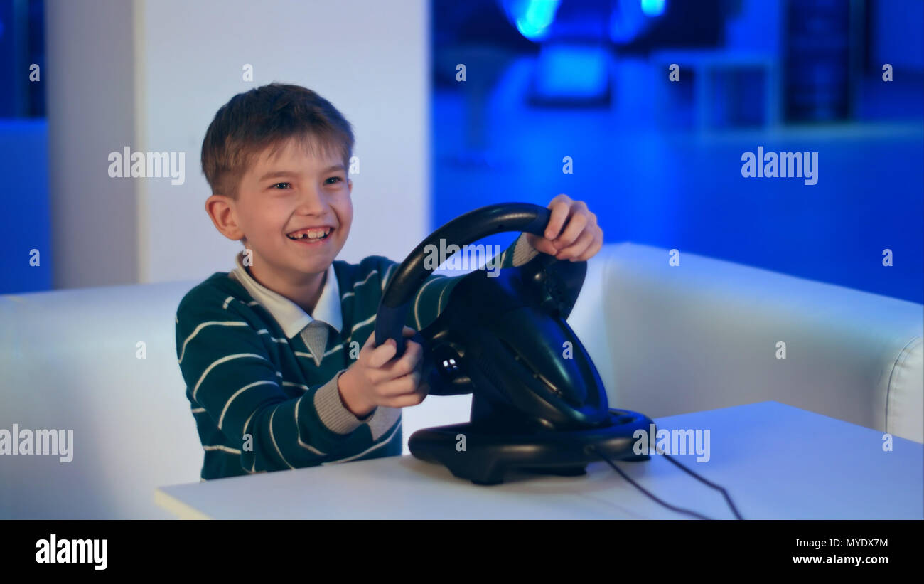 Happy excited little boy playing videogame with racing wheel Stock ...