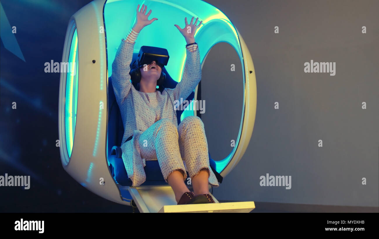 Emotional woman experiencing virtual reality in a moving interactive ...