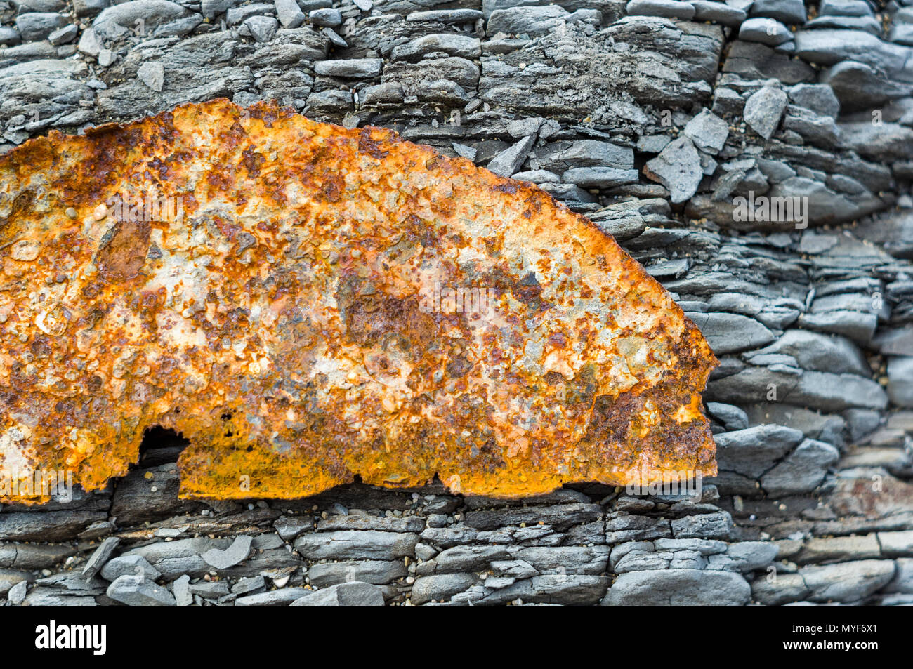 Very rusty metal on a gray cracked rock, bright sunlight, close up ...