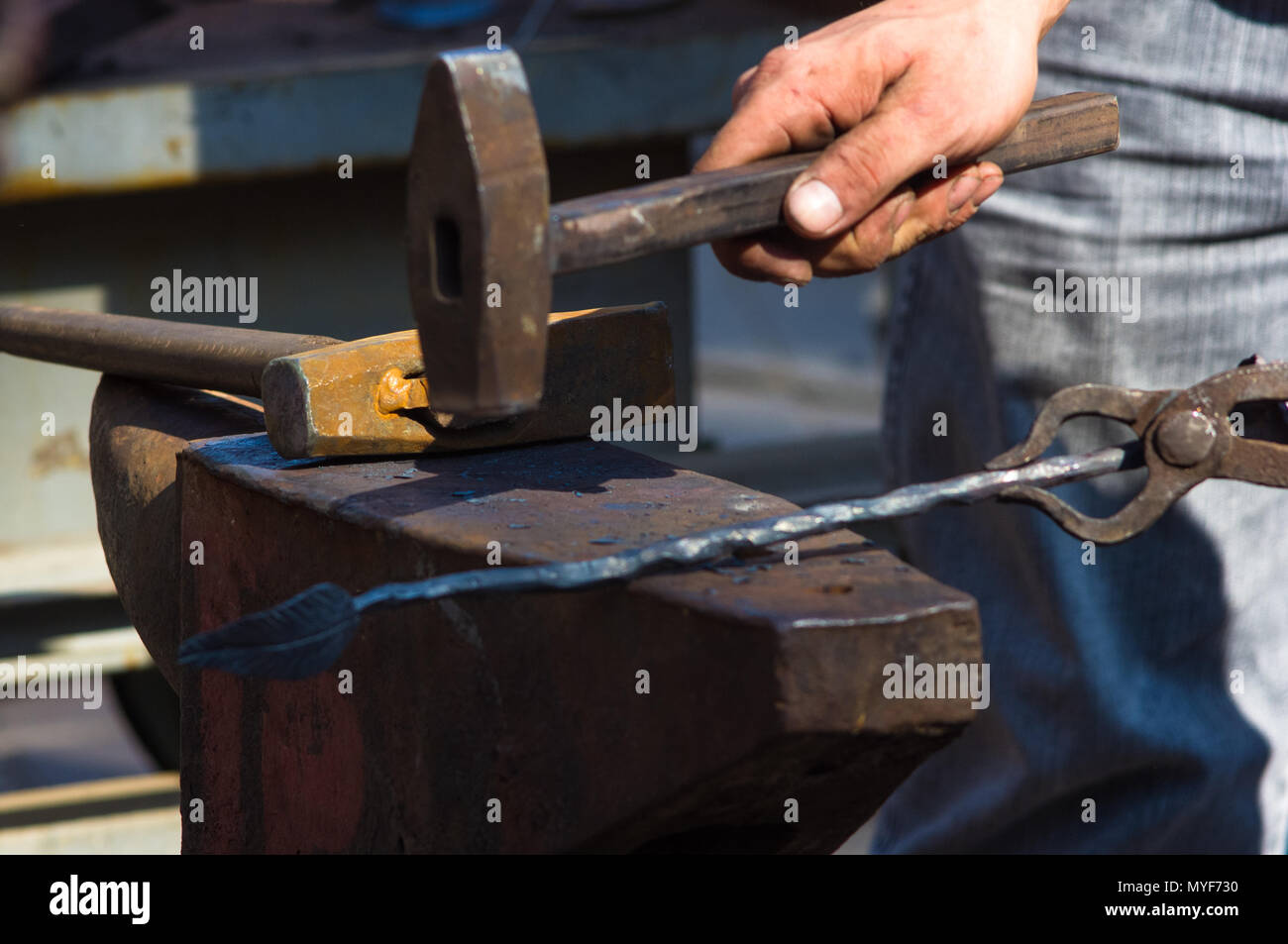 blacksmith performs the forging of hot glowing metal on the anvil ...