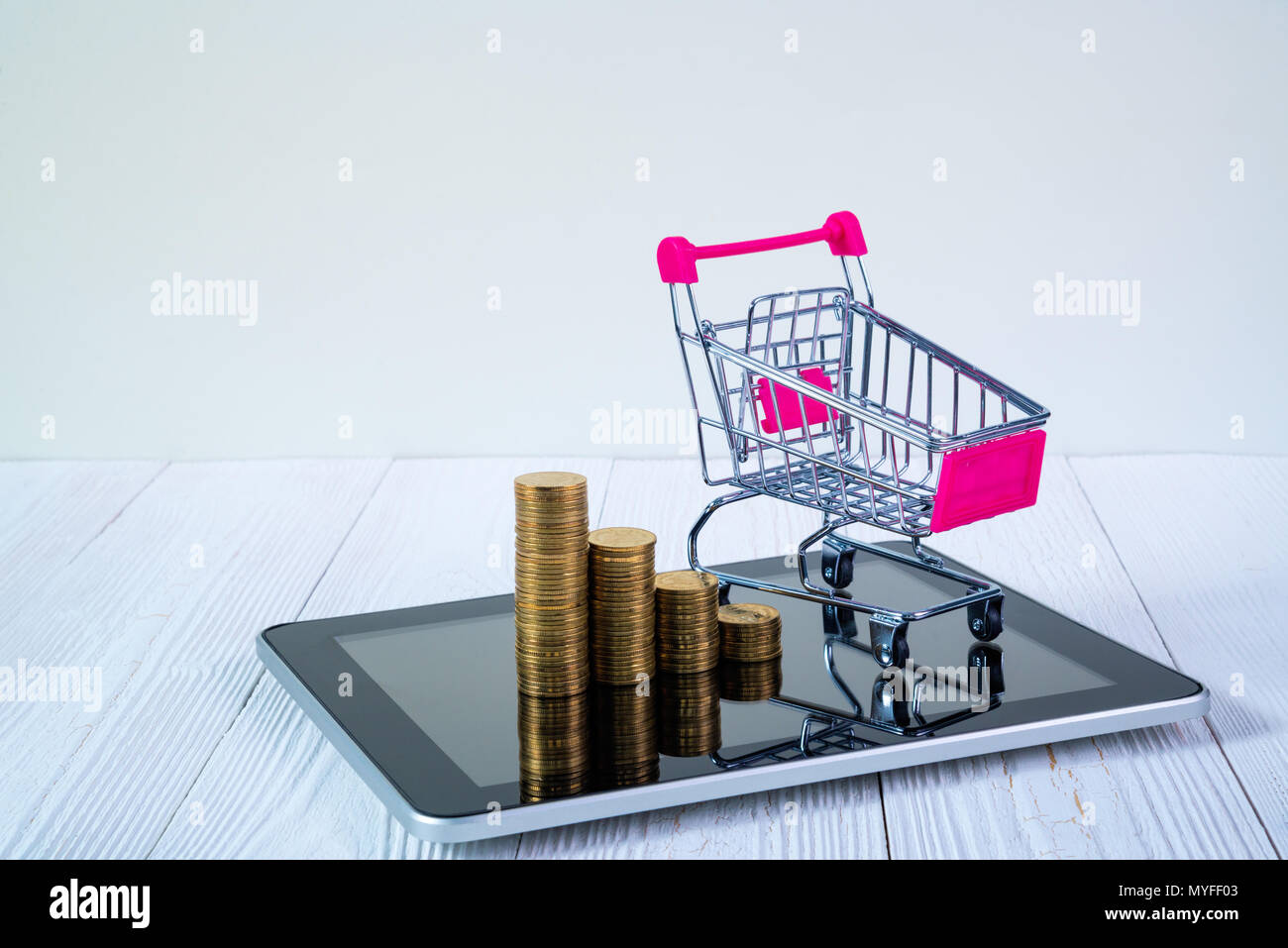 Step of coin stack and shopping cart or supermarket trolley on tablet ...