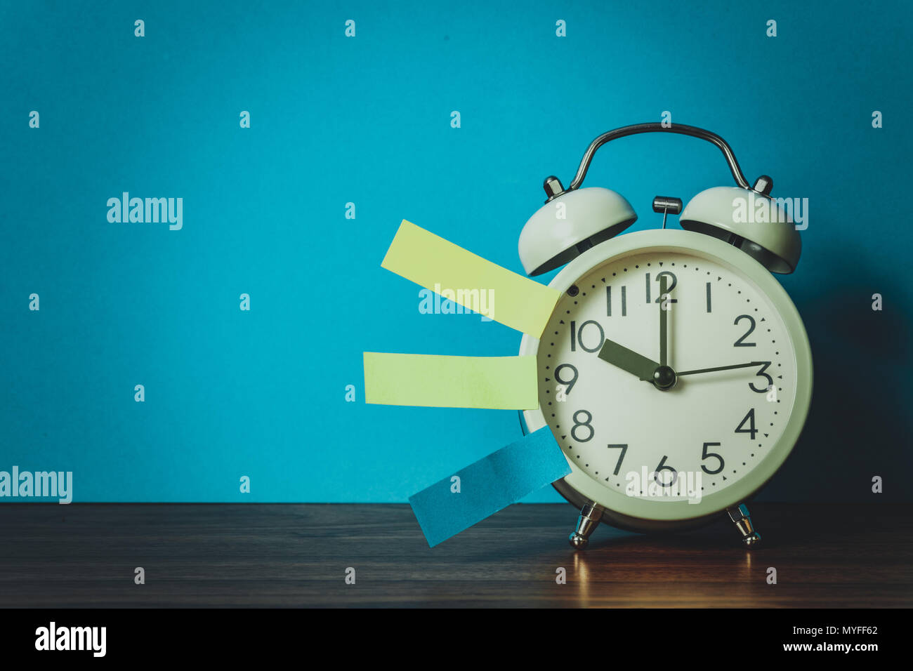Note paper sticky and vintage alarm clock on table with copy space for ...