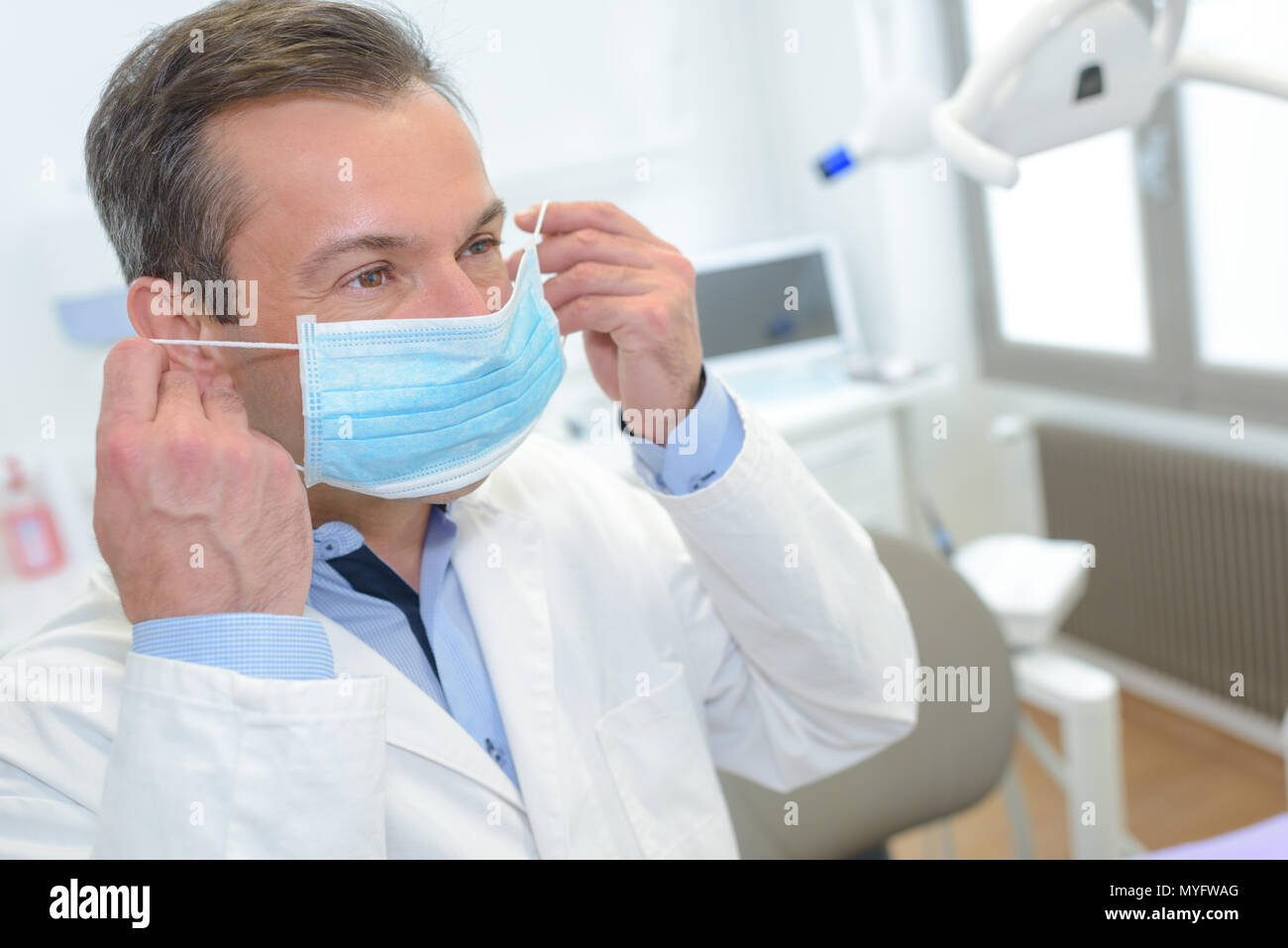male dentist putting on mask Stock Photo - Alamy