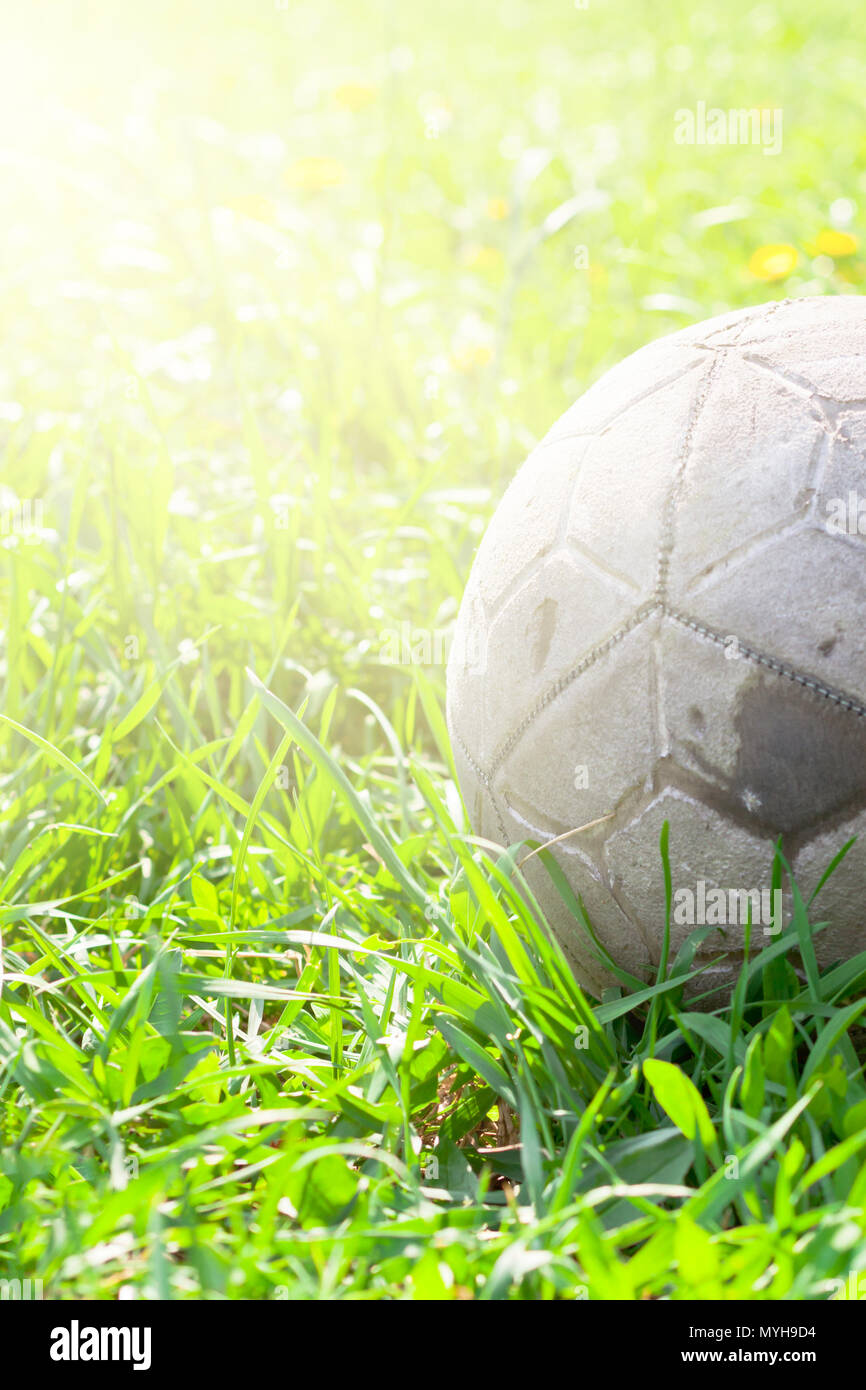 Old soccer ball forgotten in the green grass field. The football ...