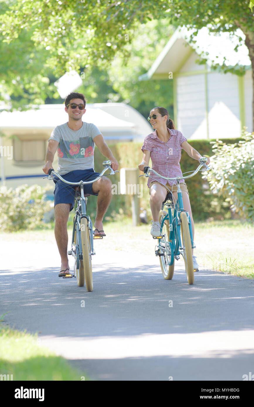 Couple riding through campsite Stock Photo - Alamy