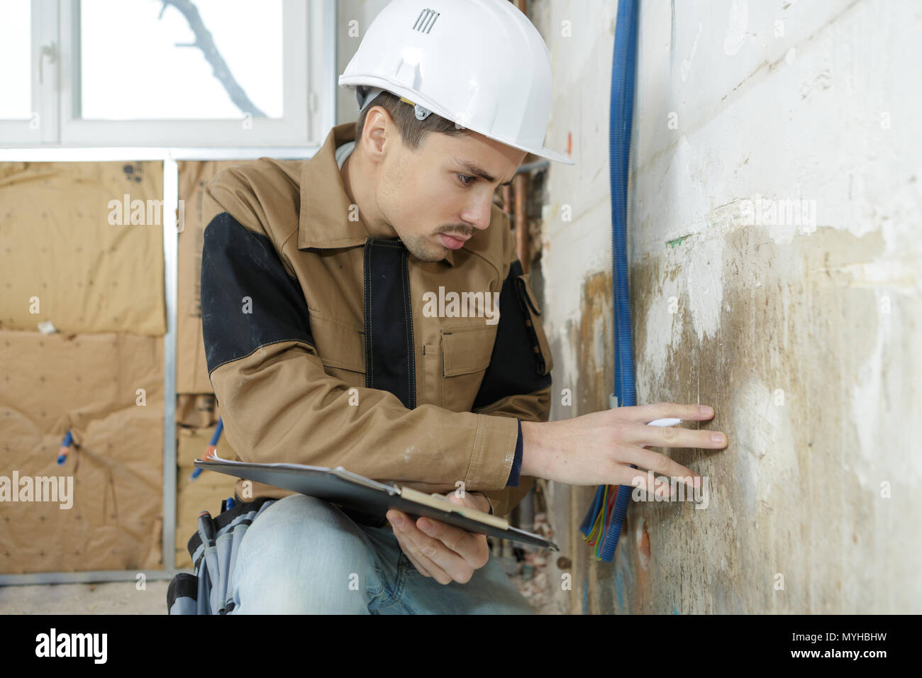 young worker checking the wall of a house Stock Photo - Alamy