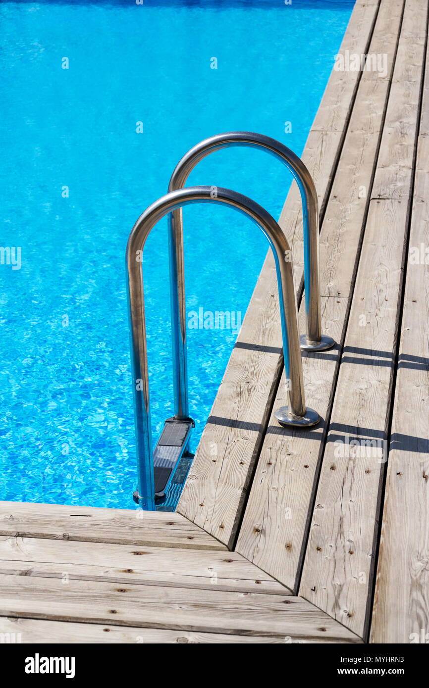 Steel ladder stairs into blue outdoor skimmer pool, wooden floor Stock ...