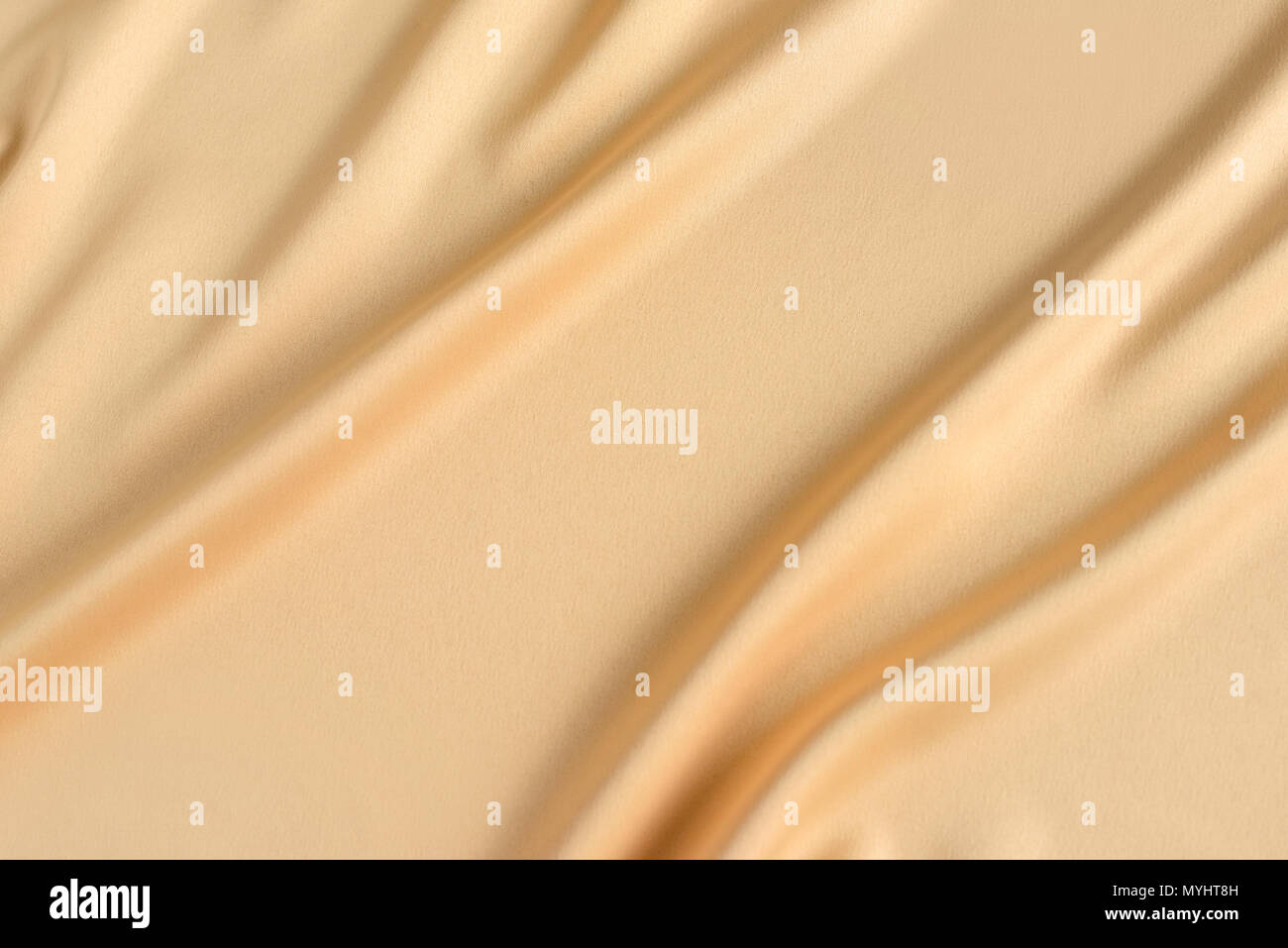Close up of ripples in gold colored silk fabric. Satin textile ...