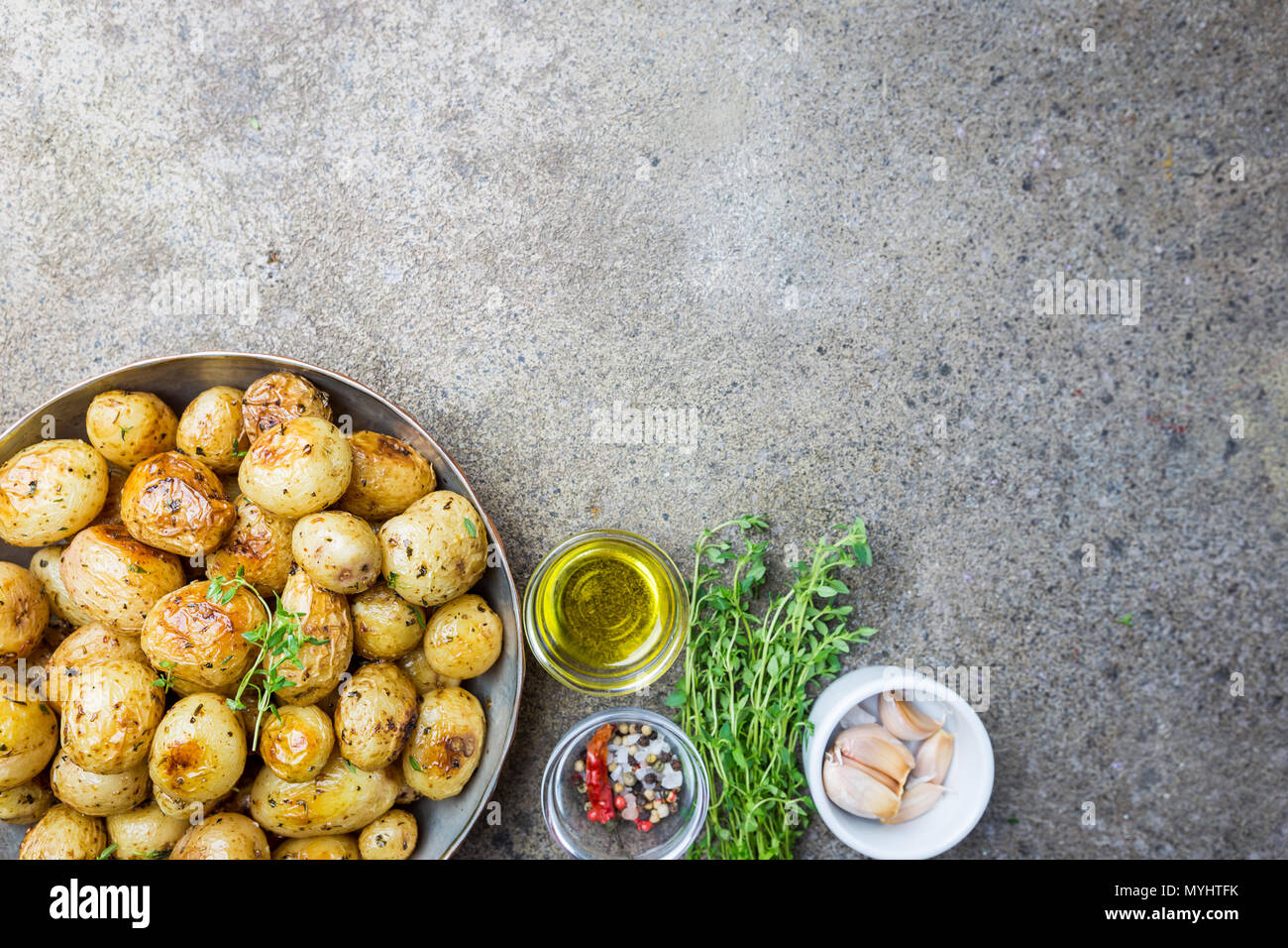Roasted whole baby potatoes with greens and garlic oil over gray stone ...