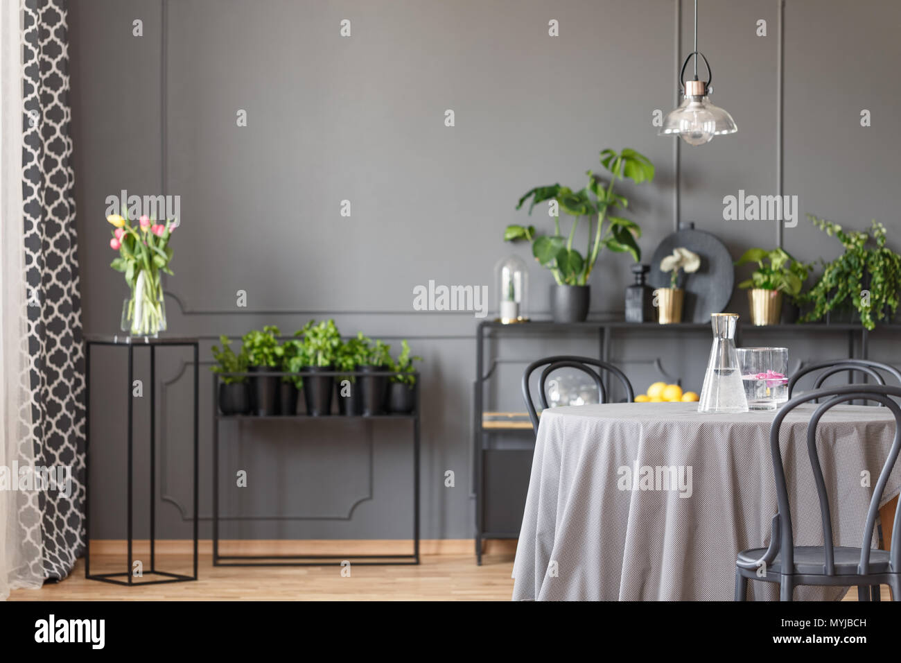 Lamp above dining table with chairs in grey apartment interior with ...