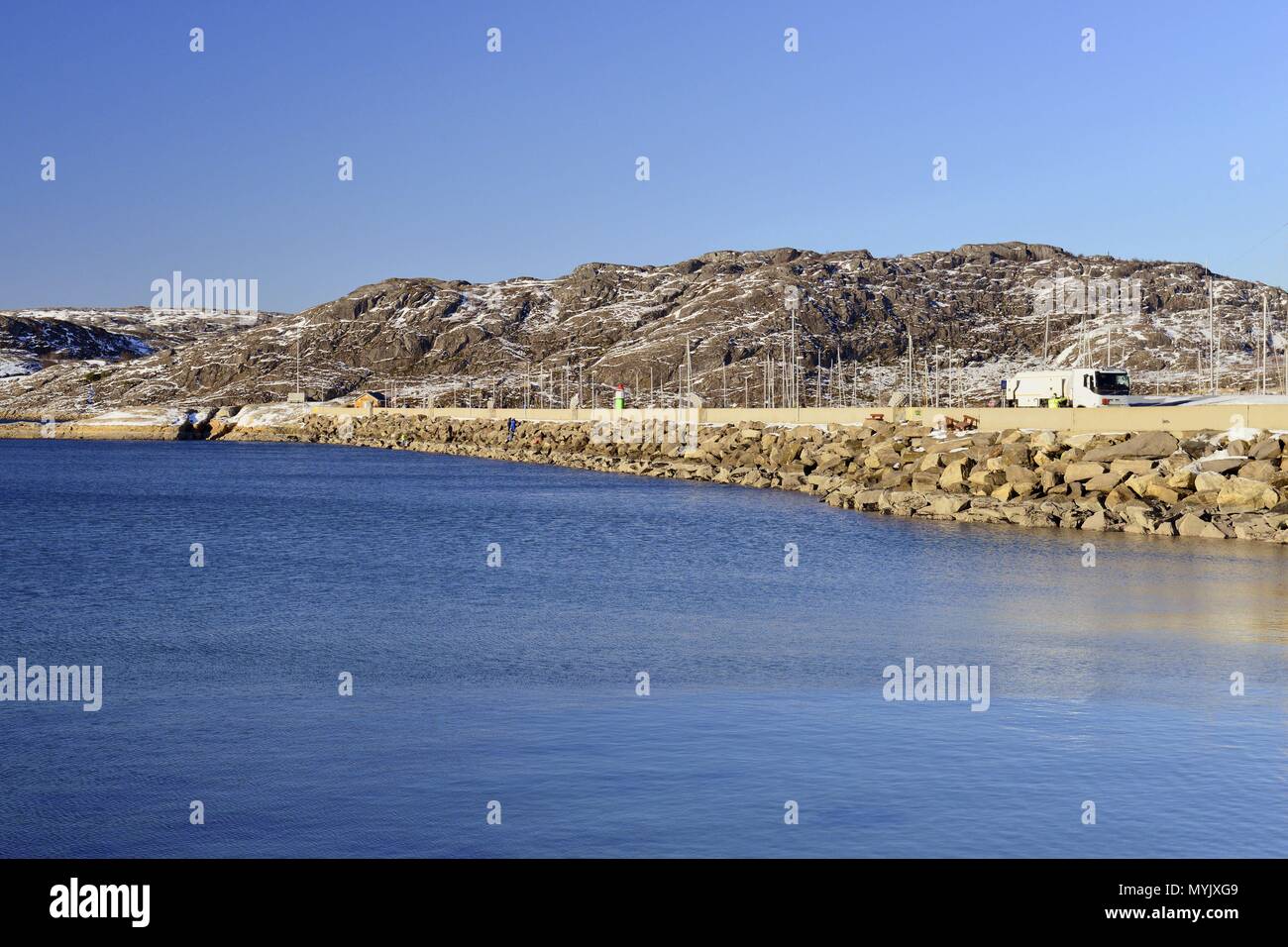 Bodø's stony pier with a white truck above and the blue sea bay in ...