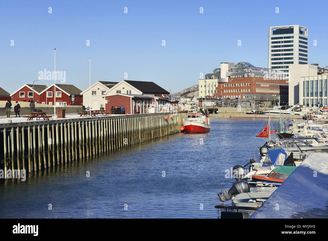 Bodø's harbour basin with wooden quay wall and boats in the blue water ...