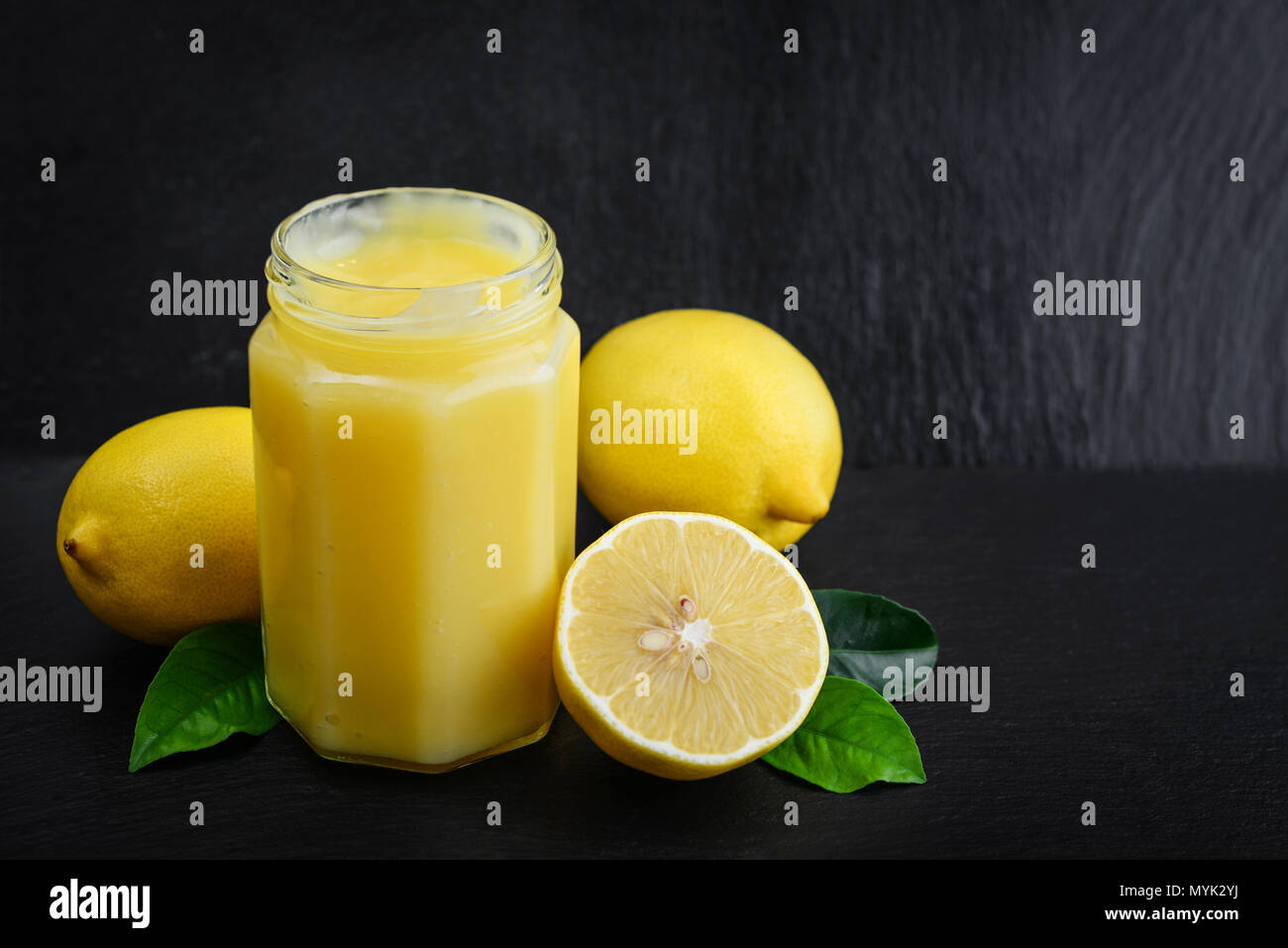 Lemon curd in jar with fresh lemons on black slate background Stock ...